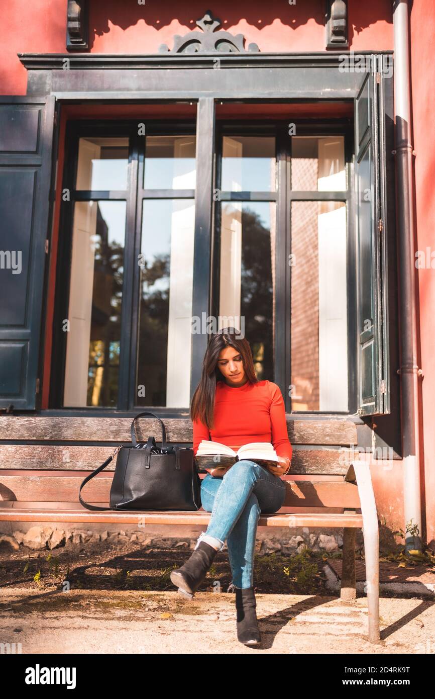Vertical shot of a young Caucasian brunette in a red stylish blouse ...