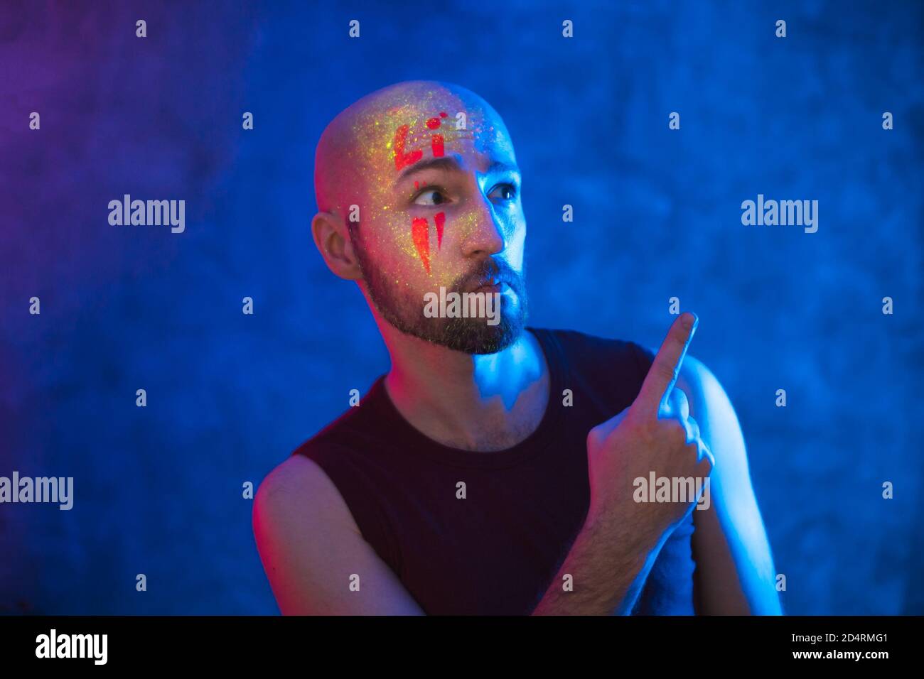 Bald-headed man with makeup points to side. Fluorescent paint in neon ...