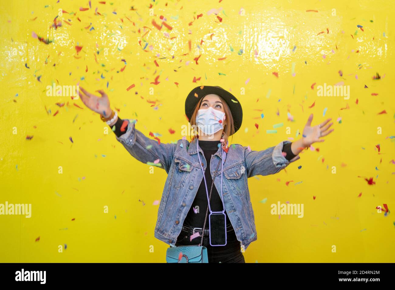 Young lady looking at confetti wearing a sanitary mask-concept of the ...