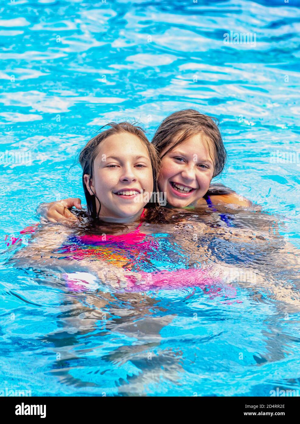 sisters and friends, these young tweens splash together in a clear blue ...