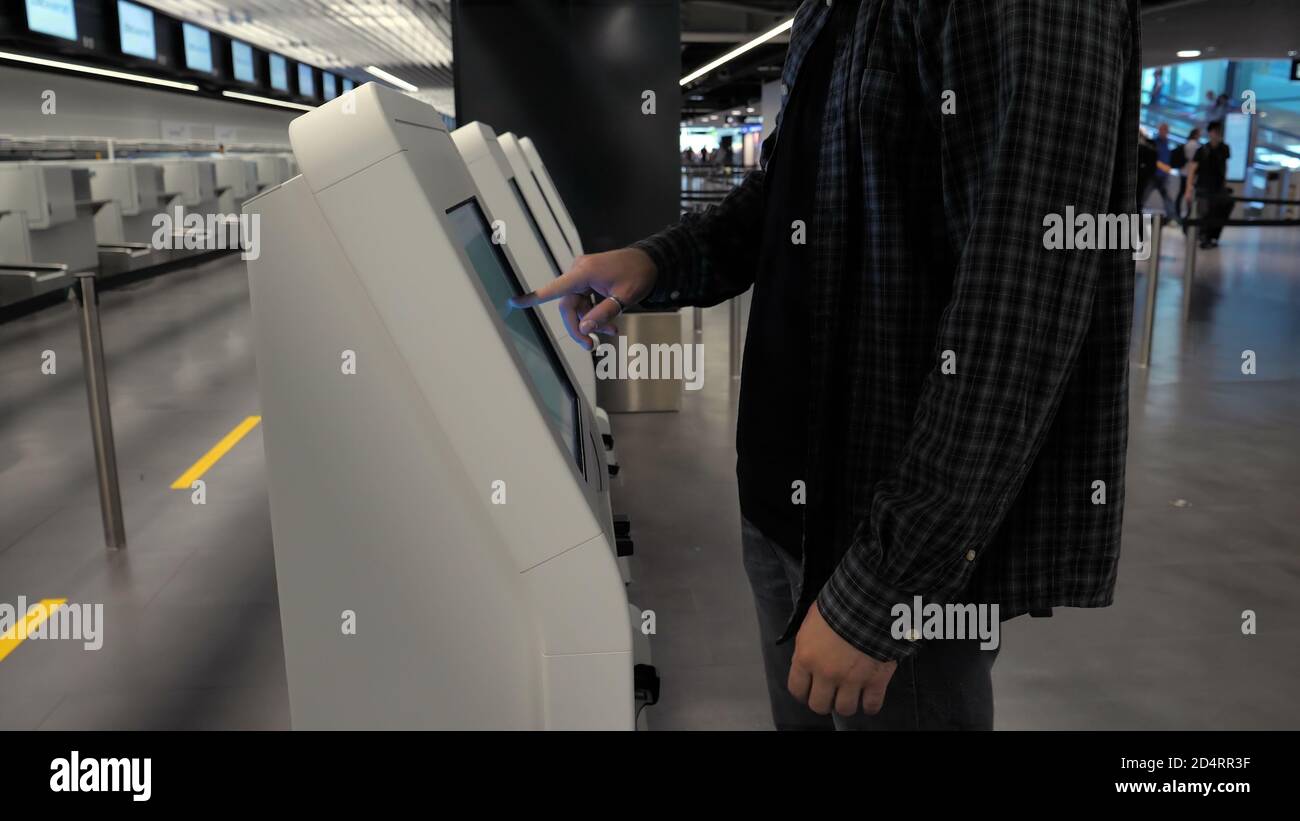 Man using the check-in machine at the airport getting the boarding pass ...
