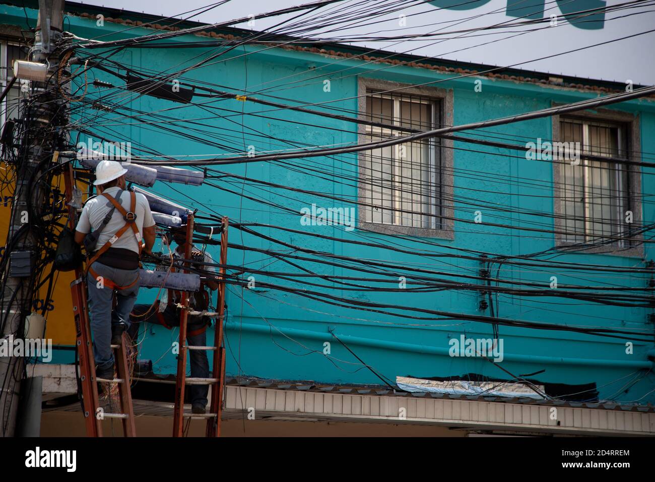 Construction worker on a ladder fixing electrical lines Stock Photo - Alamy