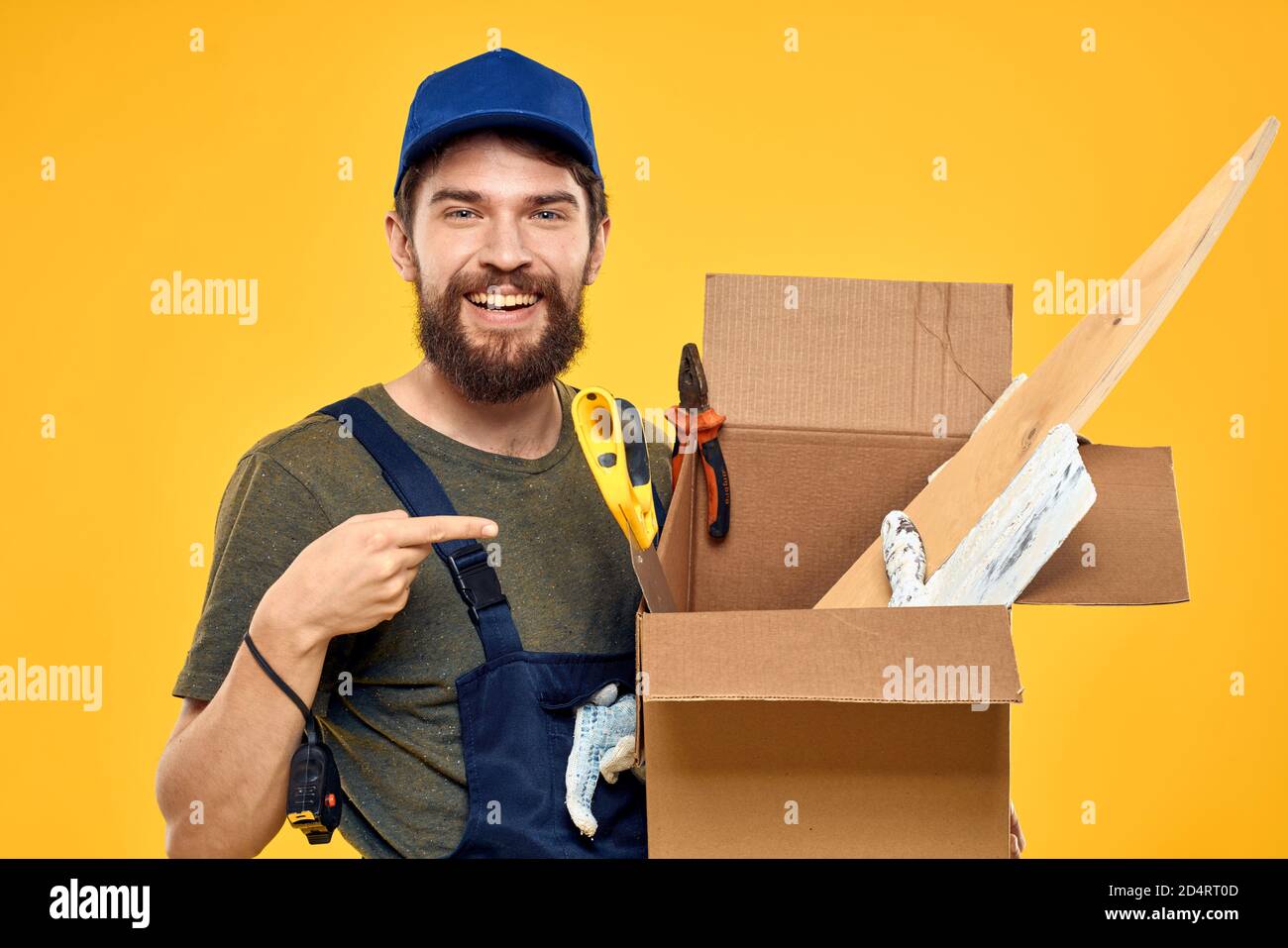 A man in a working form a box with loading tools yellow background ...