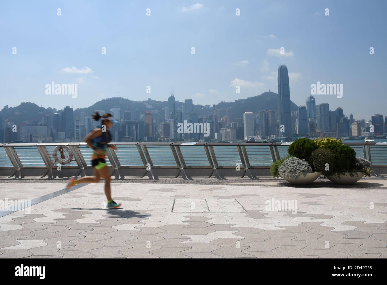 Girl doing jogging on Avenue of Stars with the Hong Kong island skyline ...