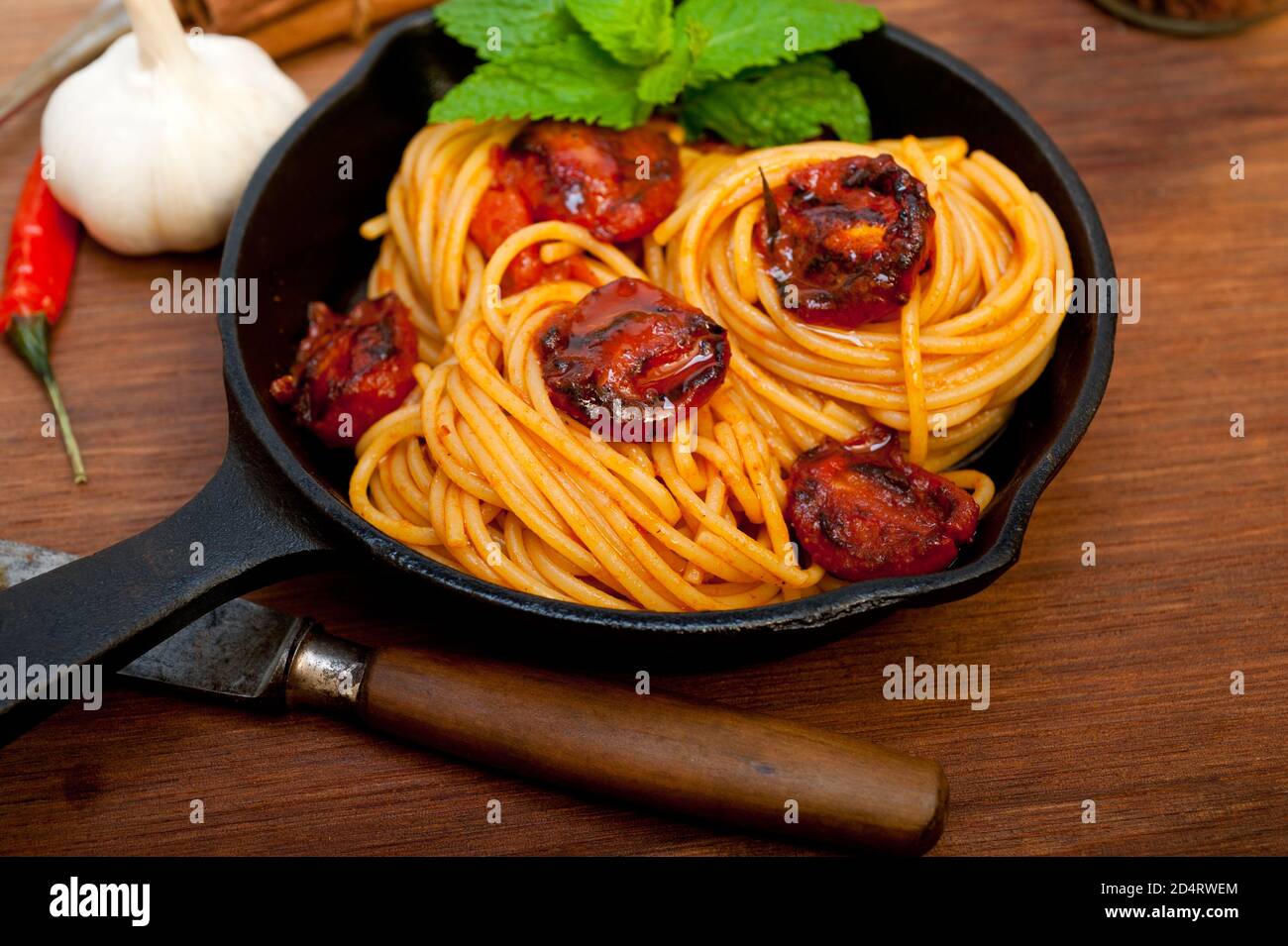 italian spaghetti pasta and tomato with mint leaves on iron skillet ...