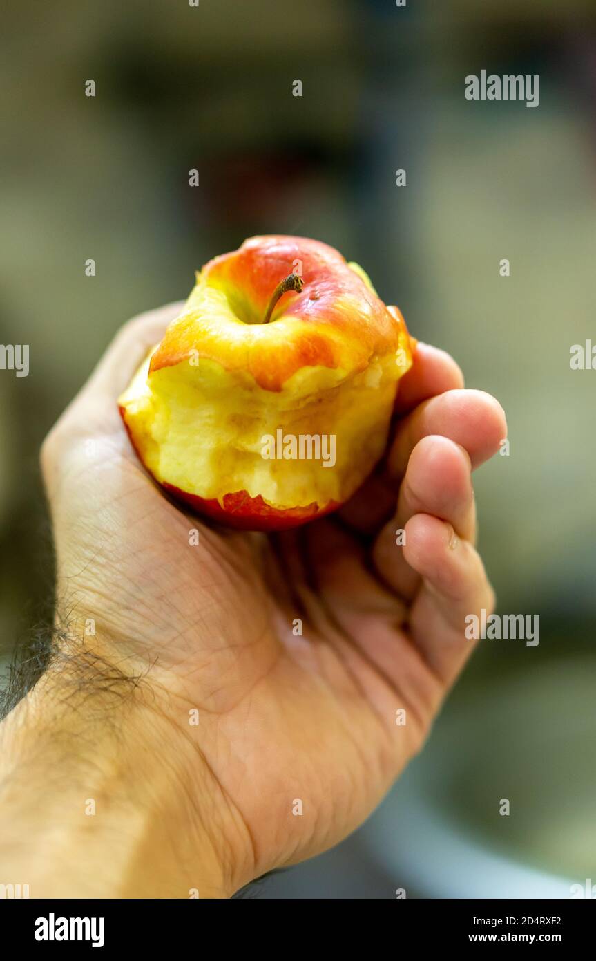 Vertical shot of a bitten apple in a hand Stock Photo - Alamy