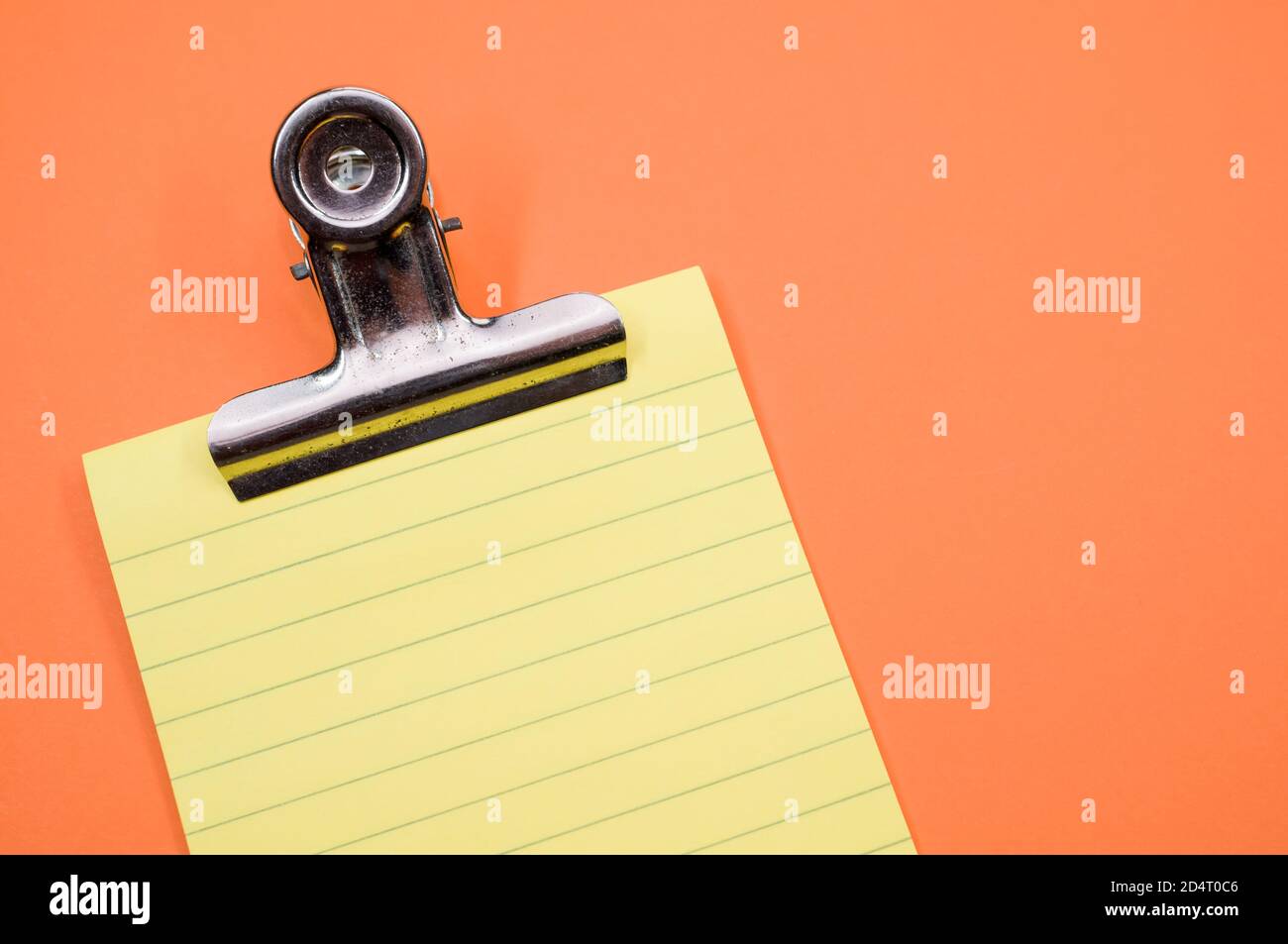 Top view of a notepad with a paper clipper isolated on an orange ...