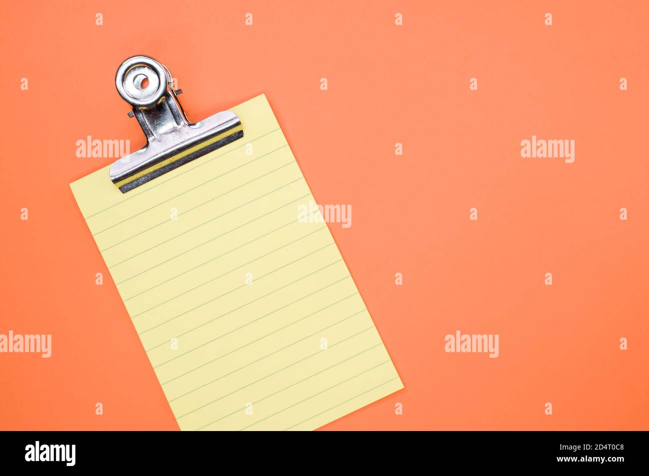 Top view of a notepad with a paper clipper isolated on an orange ...