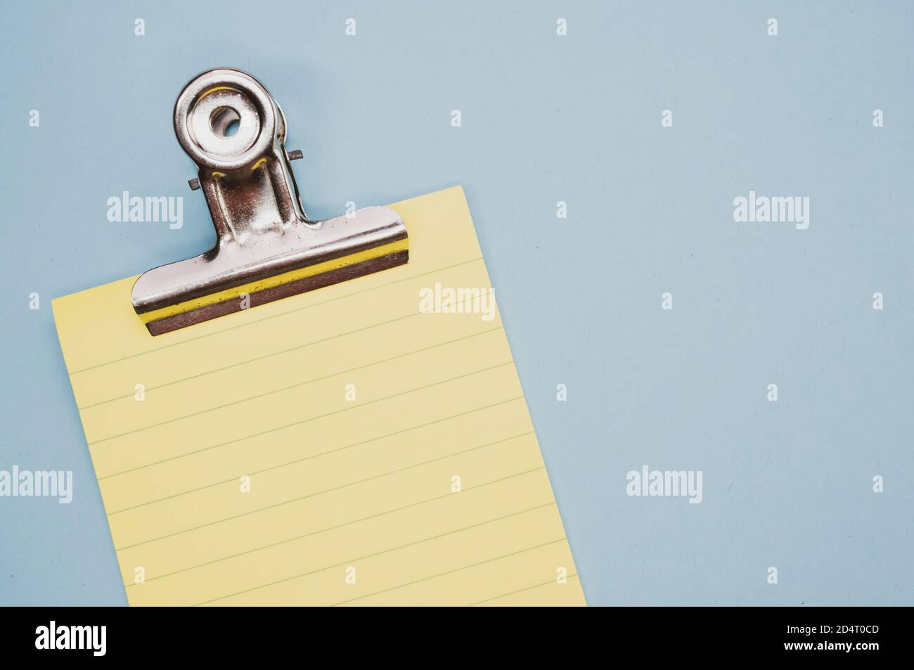 Top view of a notepad with a paper clipper isolated on a light blue ...