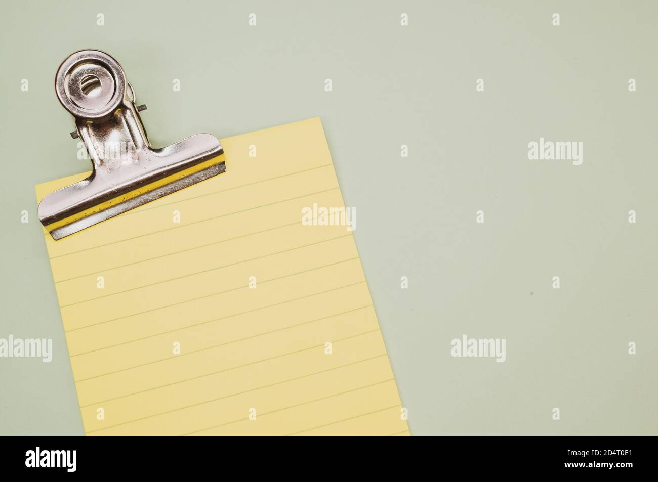 Top view of a notepad with a paper clipper isolated on a mint green ...