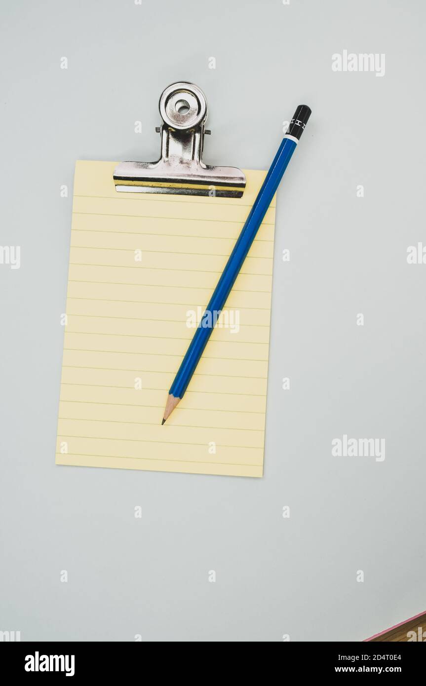 Vertical shot of a notepad with a paper clipper and a pencil isolated ...