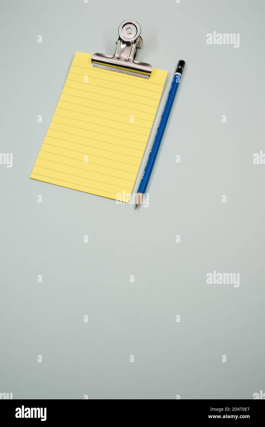 Vertical shot of a notepad with a paper clipper and a pencil isolated ...