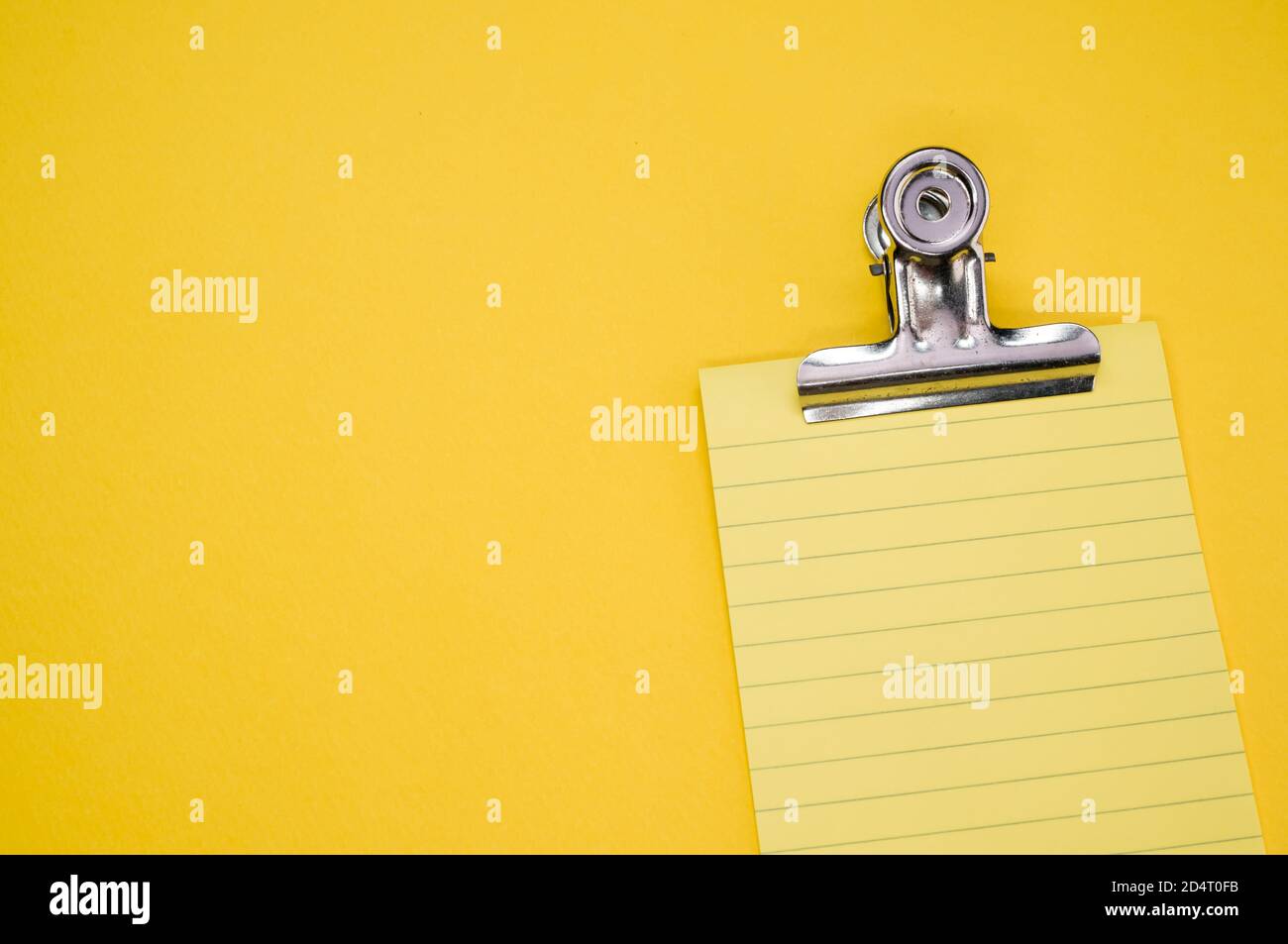 Top view of a notepad with a paper clipper isolated on a yellow ...