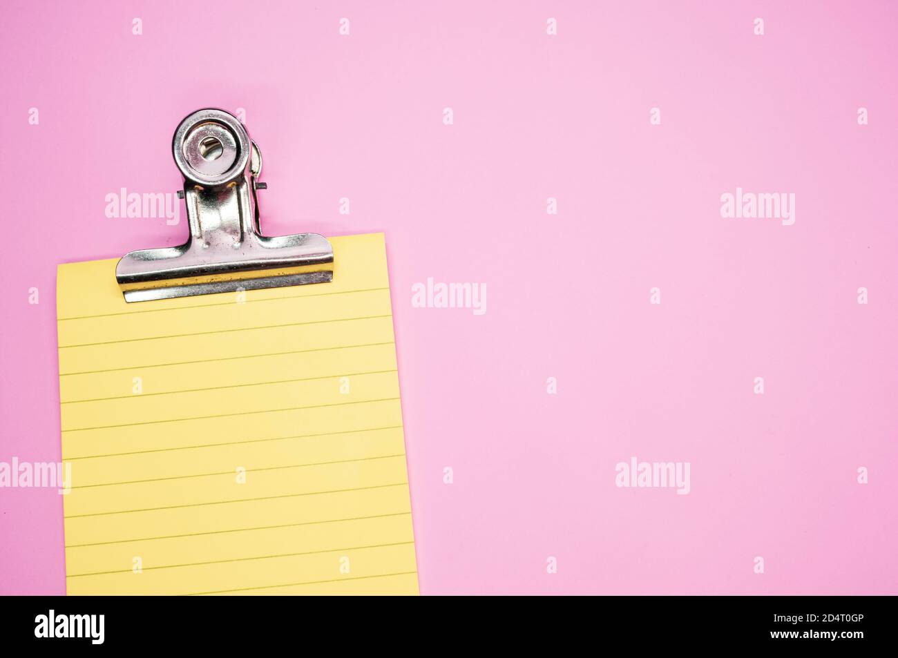 Top view of a notepad with a paper clipper isolated on a pink ...