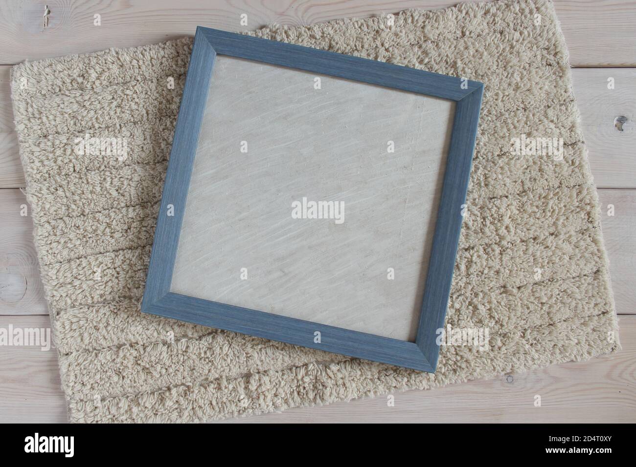 Blue photo frame on a fluffy white rug. Objects on a light wooden ...