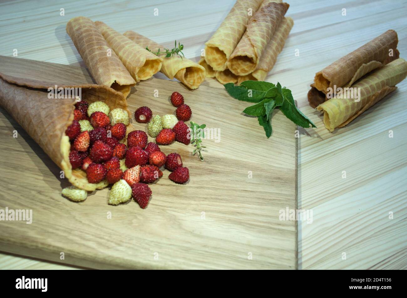 Golden waffle cone filled with strawberries and many waffle tubes, on ...