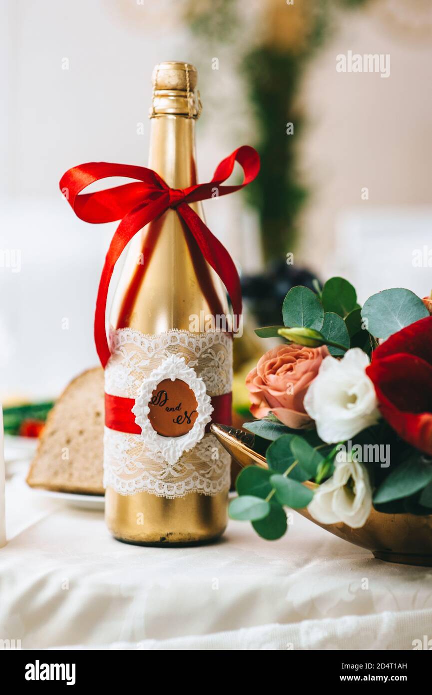 Wedding bottle of champagne painted in gold is decorated in a rustic ...