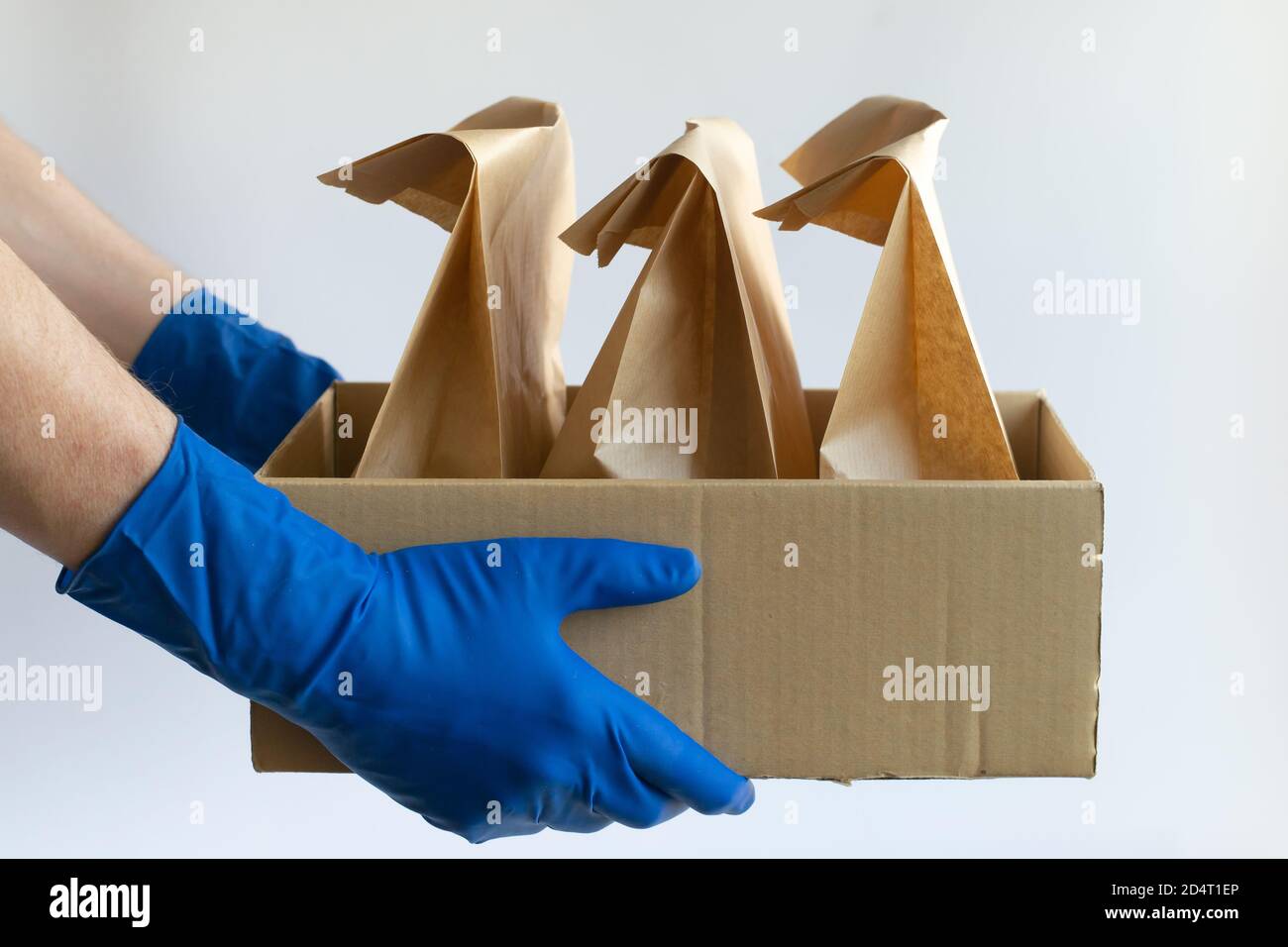 Men's hands in protective gloves hold a cardboard box with food ...