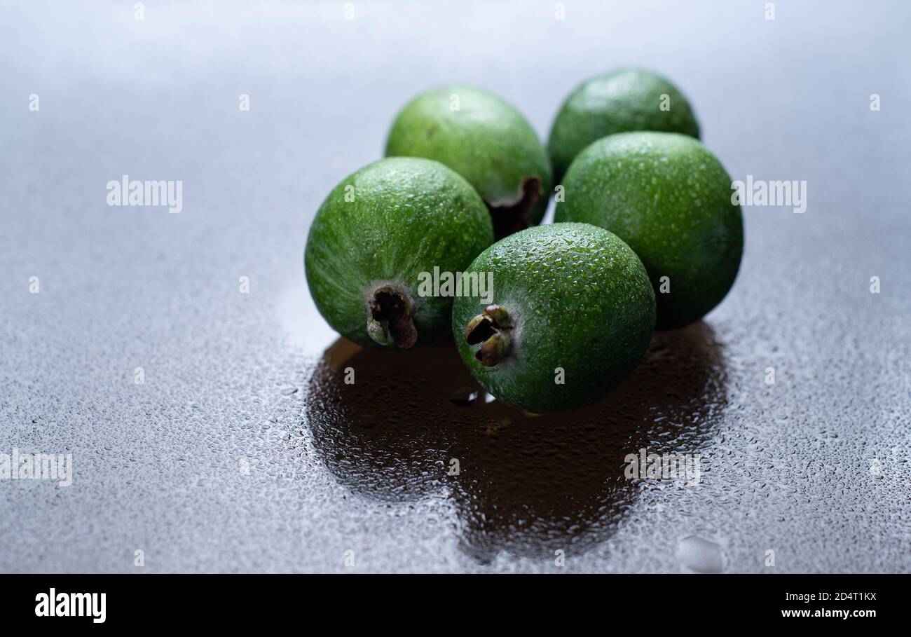 Still life of whole feijoa fruits on the damp reflective surface ...