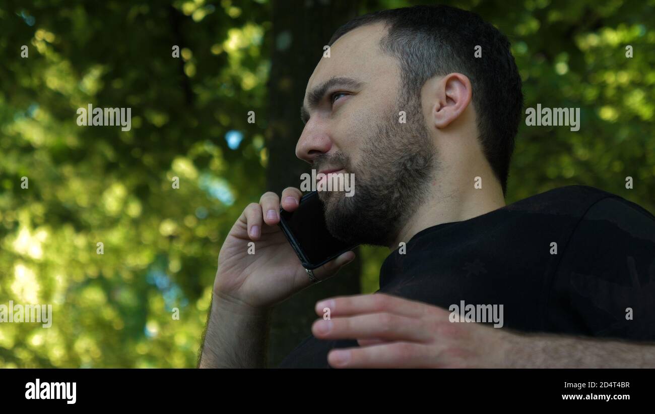 Serious guy talking on phone in the park Stock Photo - Alamy