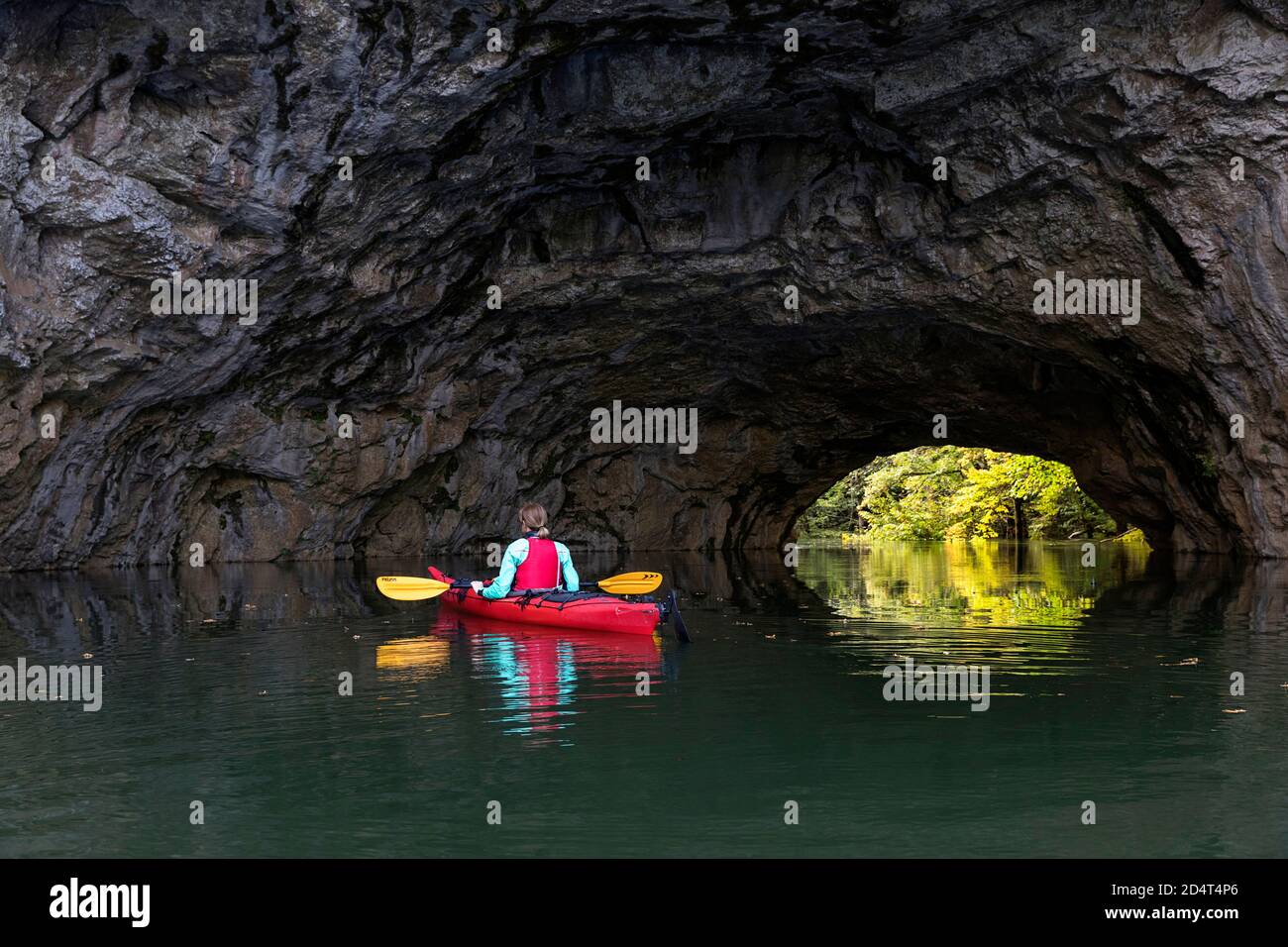 Woman under natural bridge kayaking in flooded forest at Rakov skocjan ...