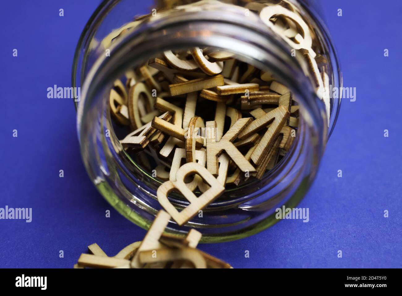Close up of tipped over glass jar with scattered alphabet letters on ...