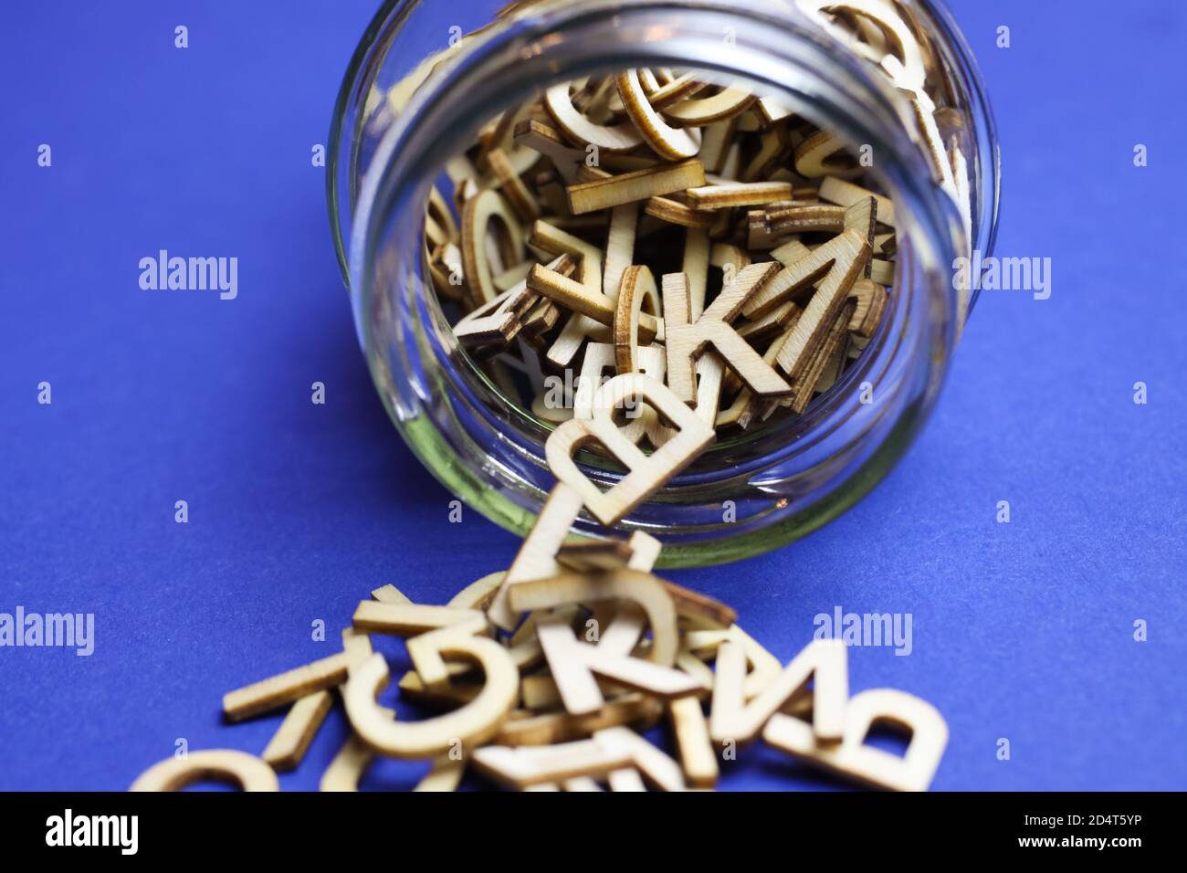 Close up of tipped over glass jar with scattered alphabet letters on ...