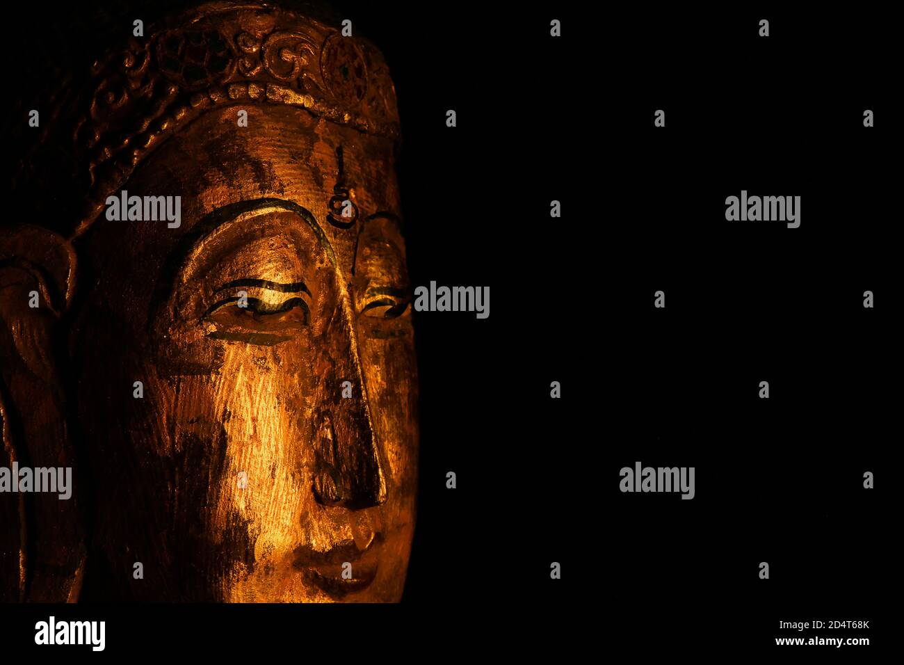 Closeup of isolated illuminated golden Buddha face mask on black blank ...