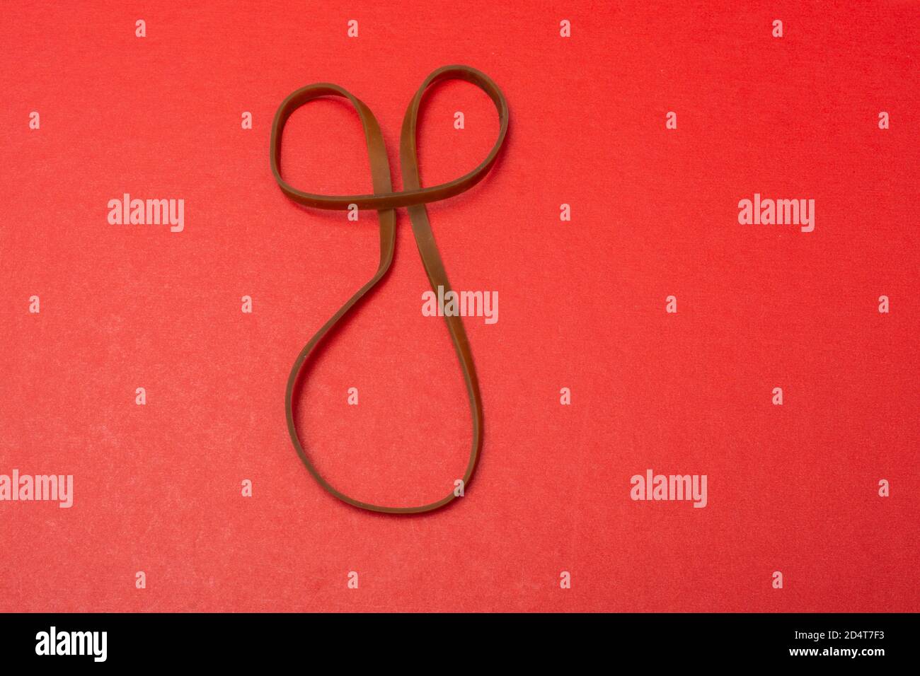 Top view of a single rubber band on a red background Stock Photo - Alamy