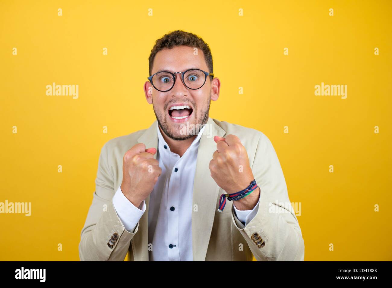 Young handsome businessman wearing suit over isolated yellow background ...