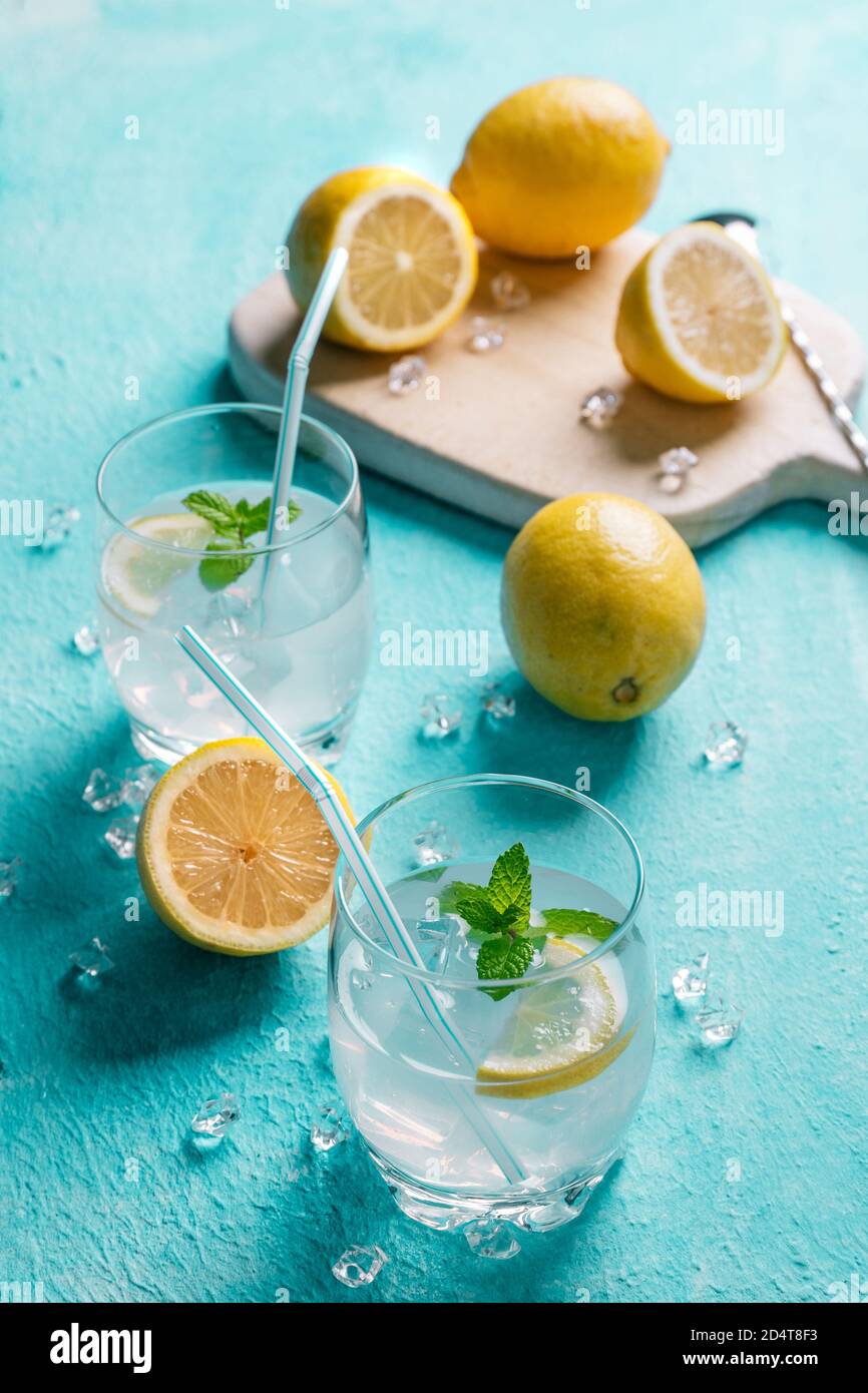 Glass of lemonade next to lemons, blue background Stock Photo - Alamy