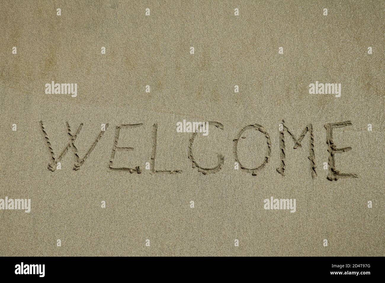 Inscription welcome on a wet sand. Welcome, texture on the beach sand ...