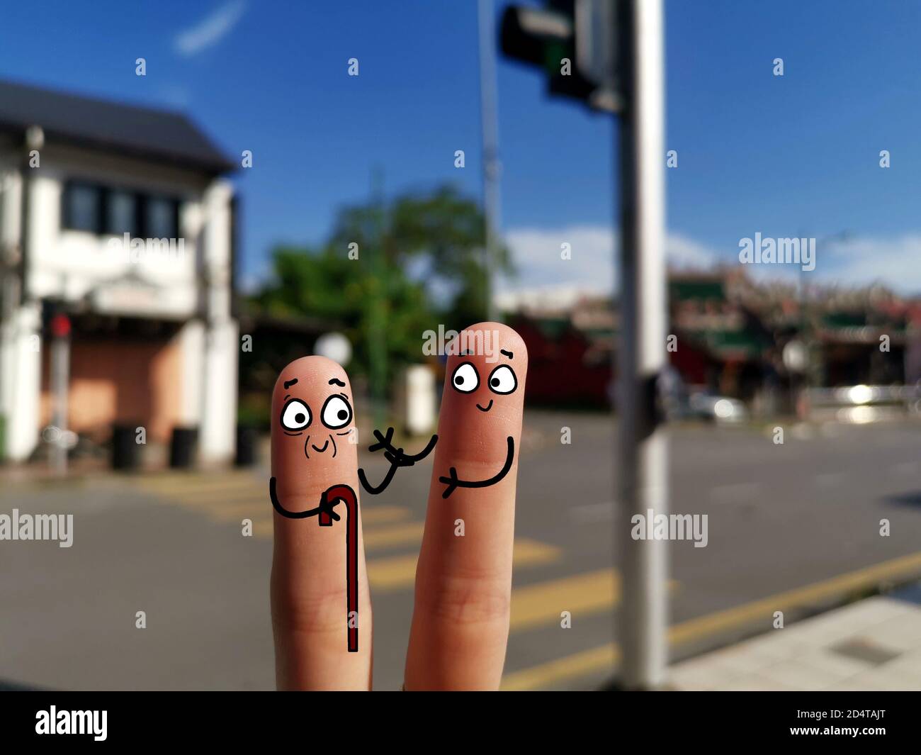 Two fingers are decorated as two person by the roadside. A young man is ...