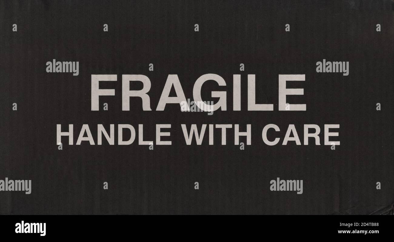 fragile handle with care warning sign on black corrugated cardboard box ...