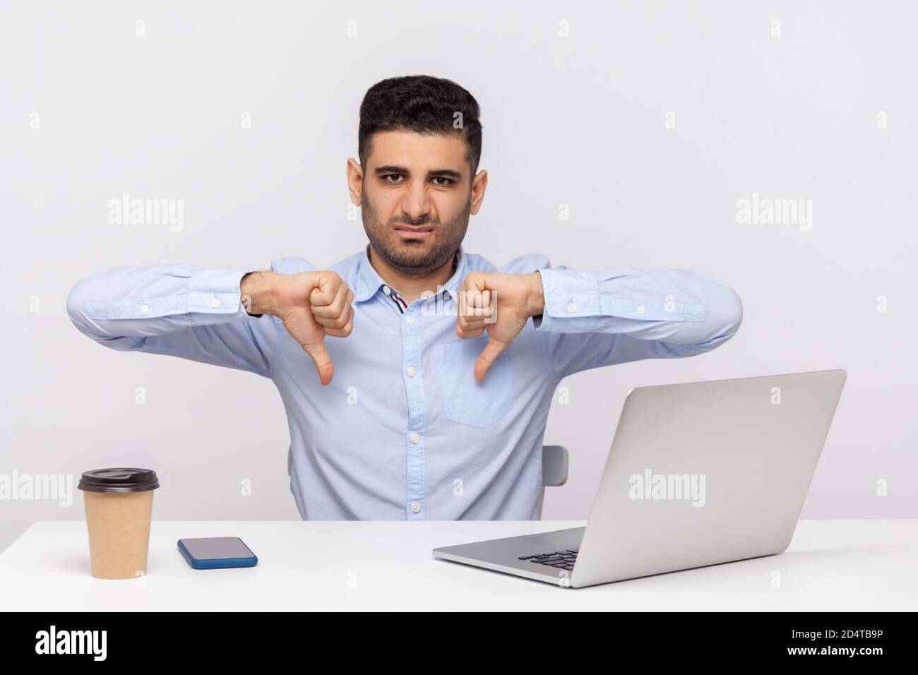 Dislike! Displeased businessman sitting office workplace showing thumbs ...