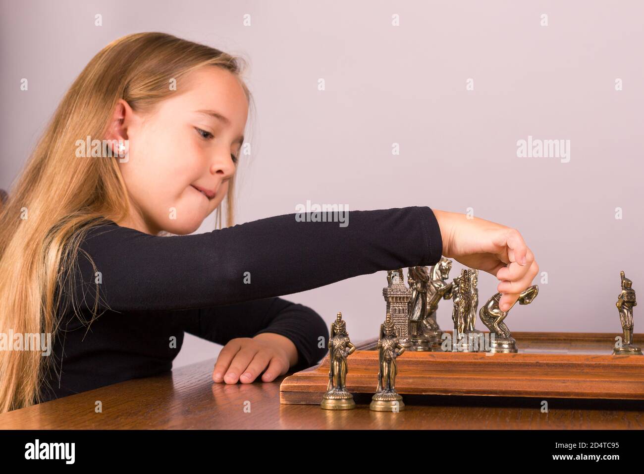 Profile portrait of young girl playing chess moving a pawn on the board ...