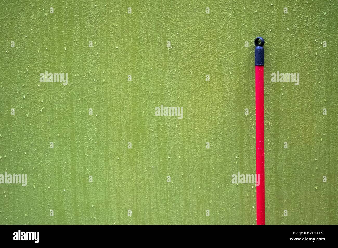 Red mop handle rest against wet green wall in the rain. Close-up Stock ...