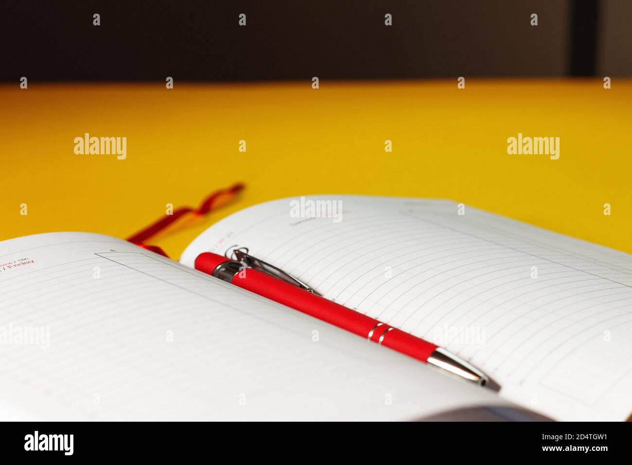 Closeup shot of an open notebook and a pen isolated on a yellow ...