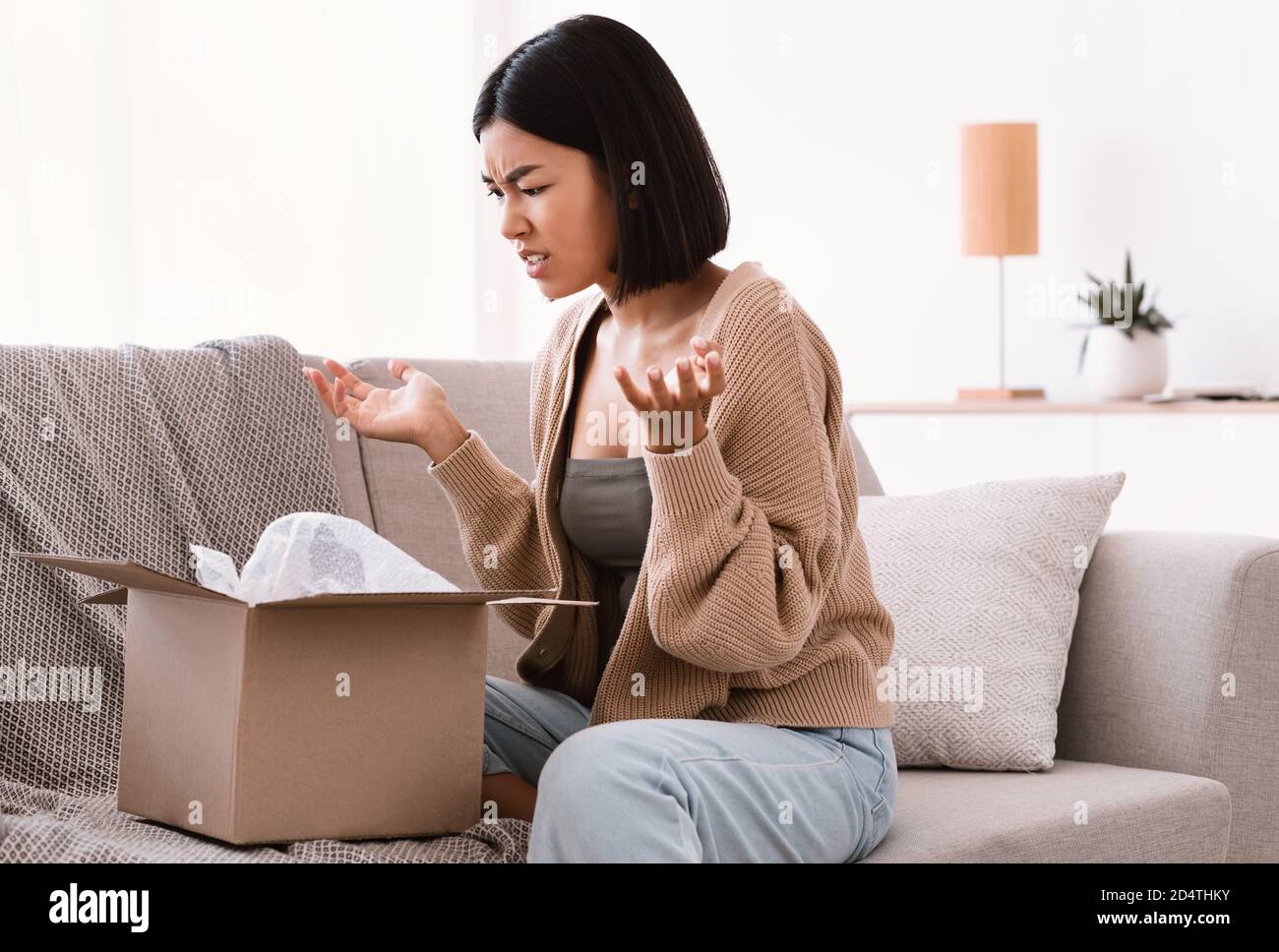 Angry asian woman unpacking wrong box, delivery mistake Stock Photo - Alamy