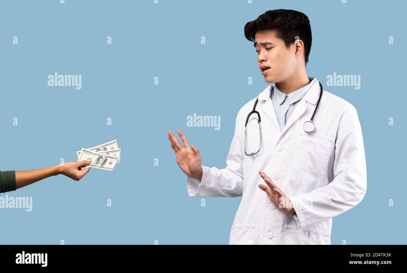 Scared asian male doctor refusing bribe from female patient Stock Photo ...