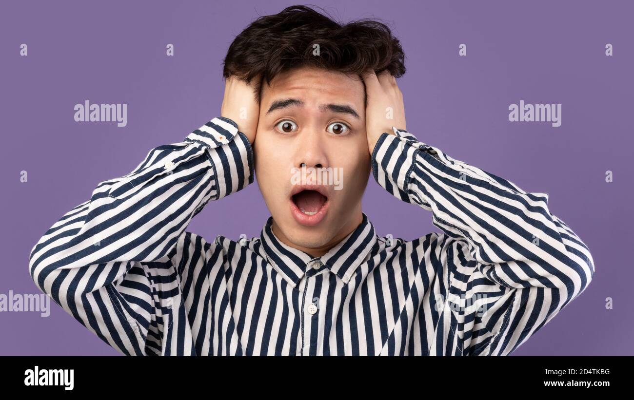 Scared asian man grimacing, screaming at purple studio Stock Photo - Alamy