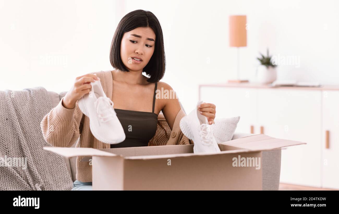 Frustrated young lady unpacking wrong package, delivery mistake Stock ...