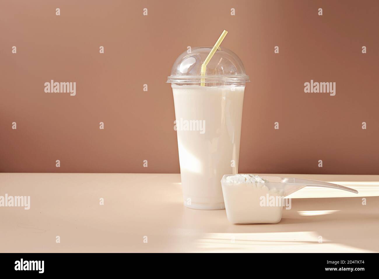 front view of whey protein cocktail in a disposable cup and scoop of ...