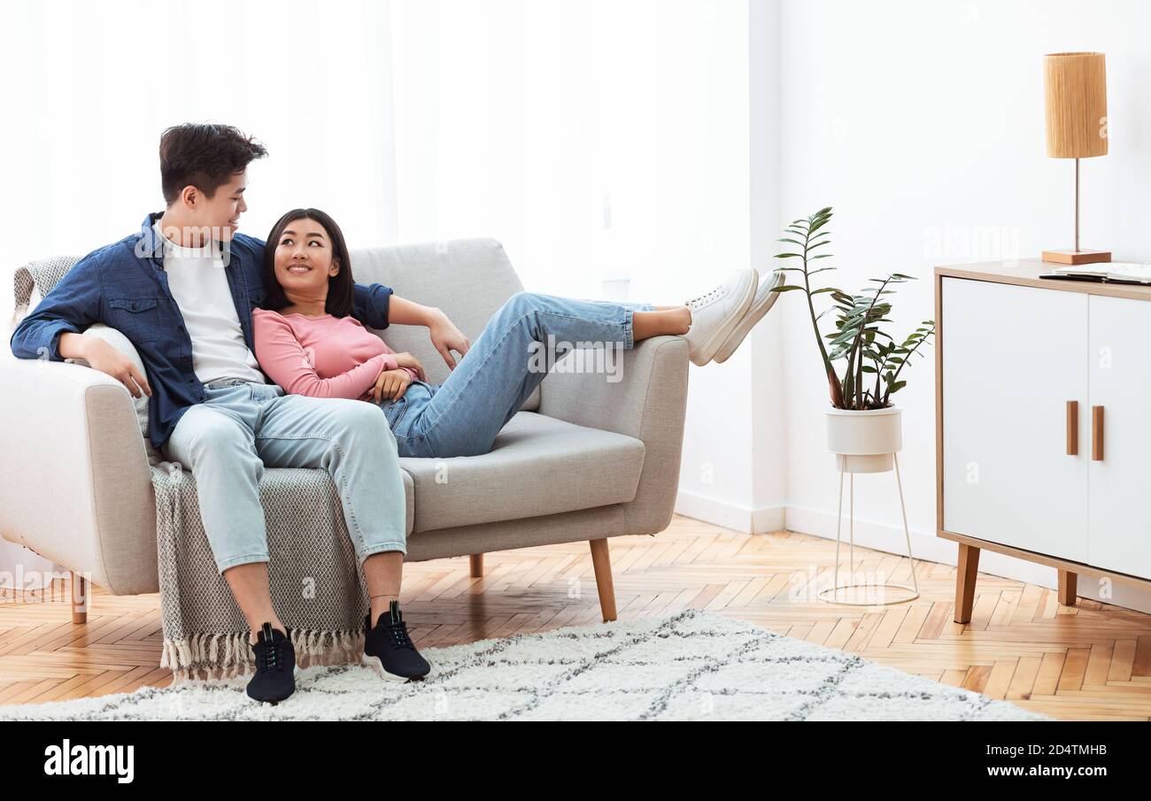 Loving young couple sitting on the couch at home hi-res stock ...