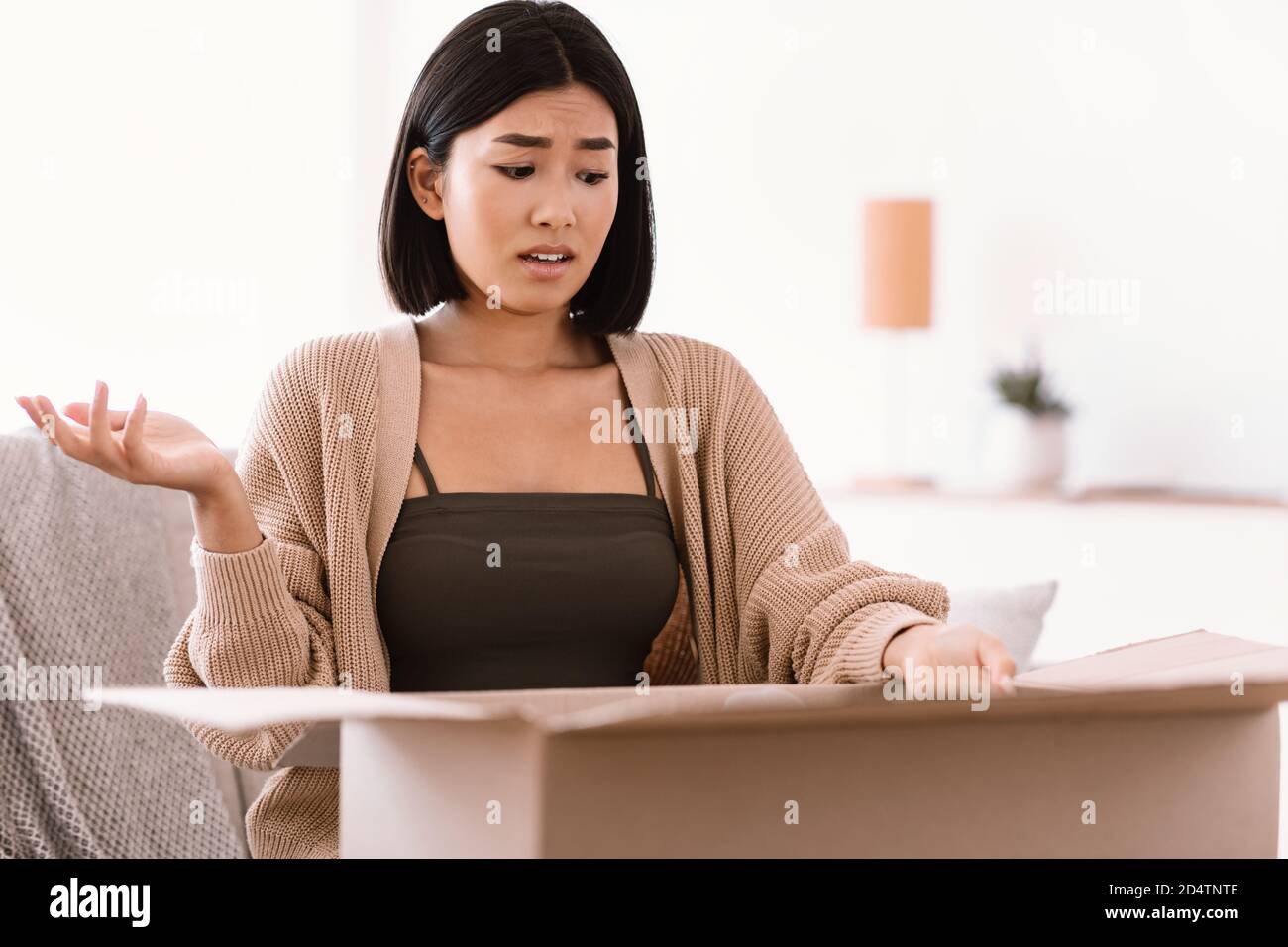 Angry young woman unpacking wrong parcel, delivery mistake Stock Photo ...