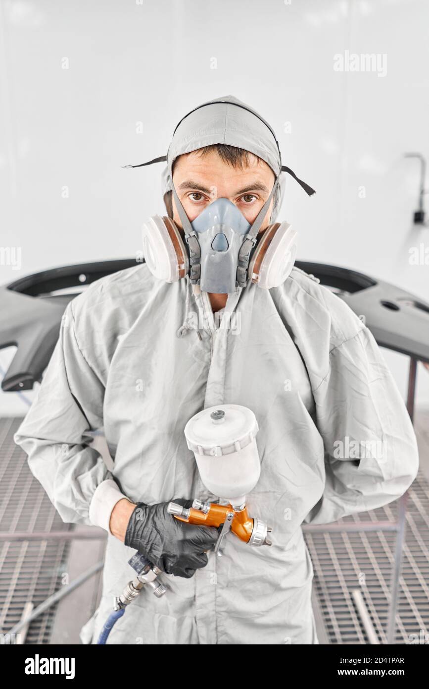 Portrait of professional auto painter. Worker painting parts of the car ...