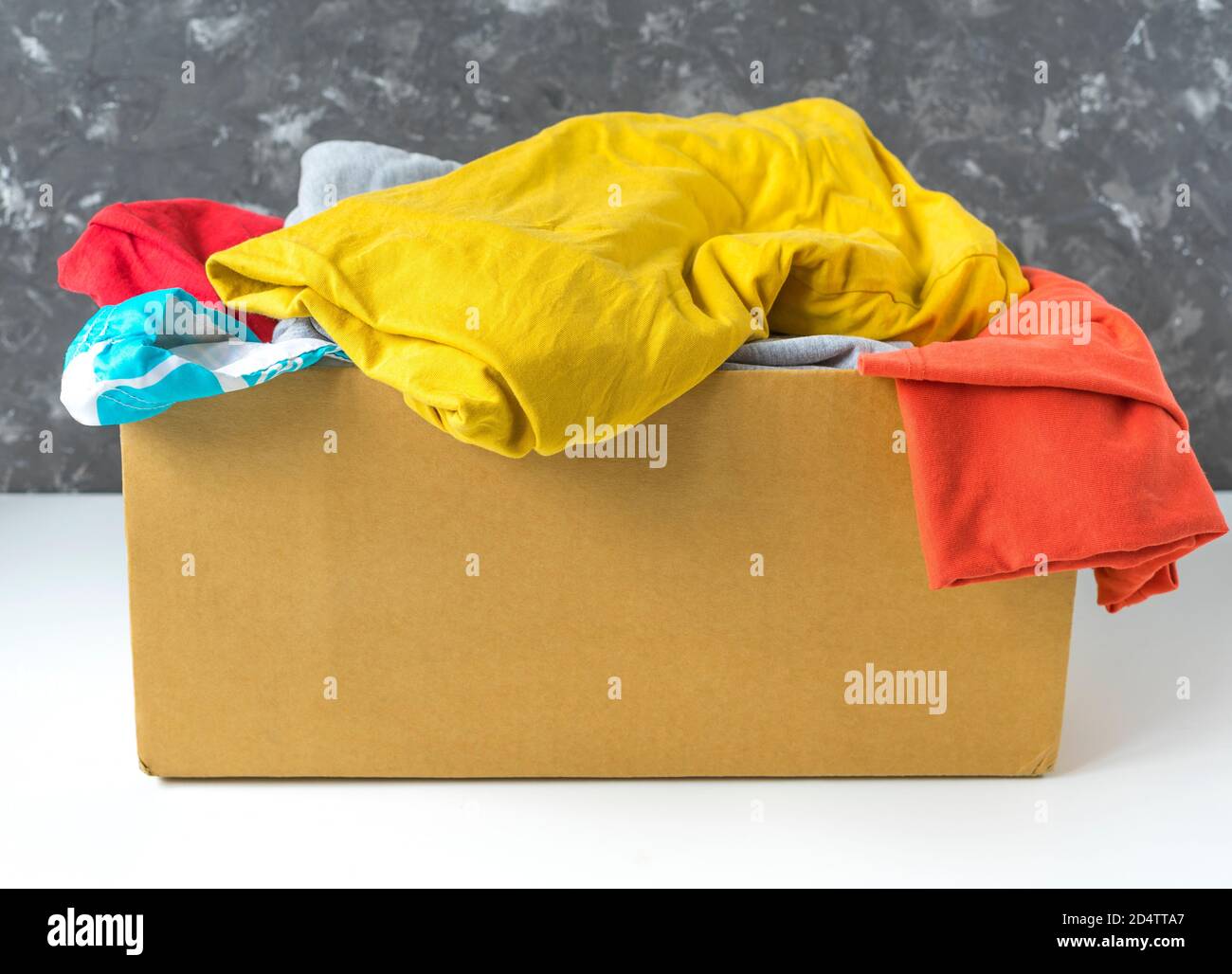 Summer clothes in a cardboard box. Seasonal clothing for shipping or ...