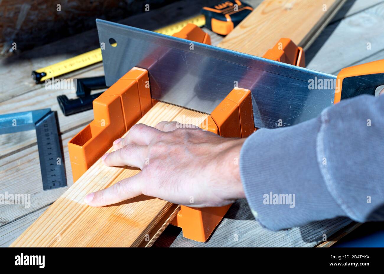 Man cutting a slat of wood using a saw and miter box. Close up view ...
