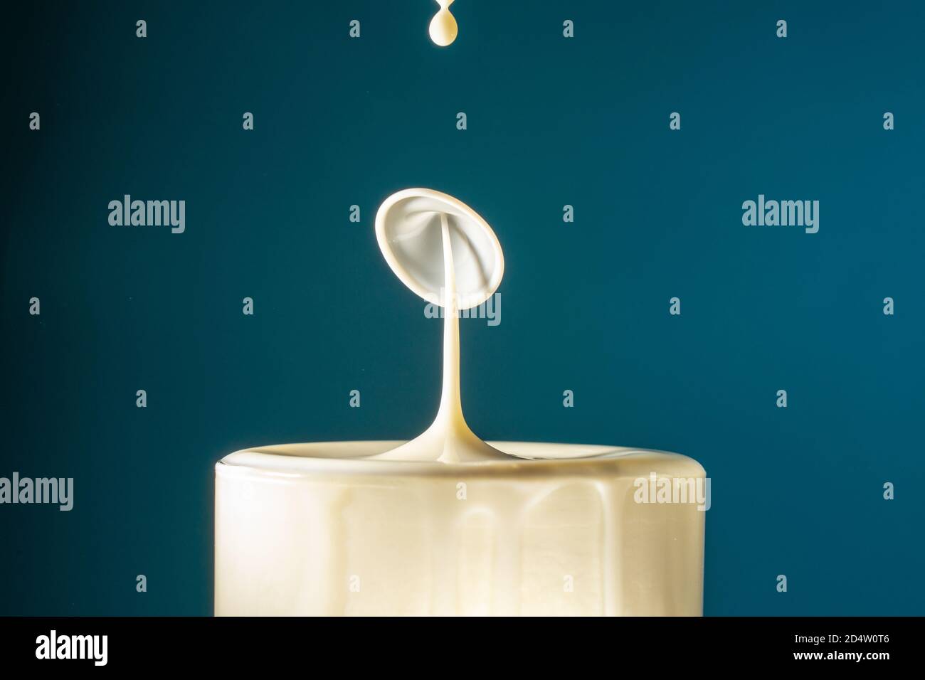 Two drops of milk fall into the long drink glass hitting each other ...