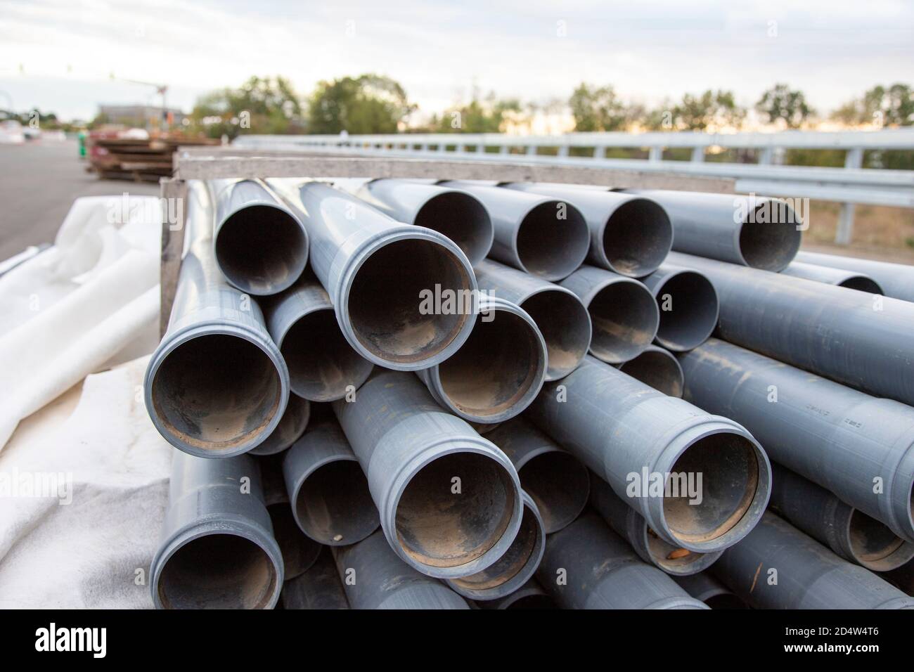 side view of a stack of grey plastic pipes for road construction Stock ...